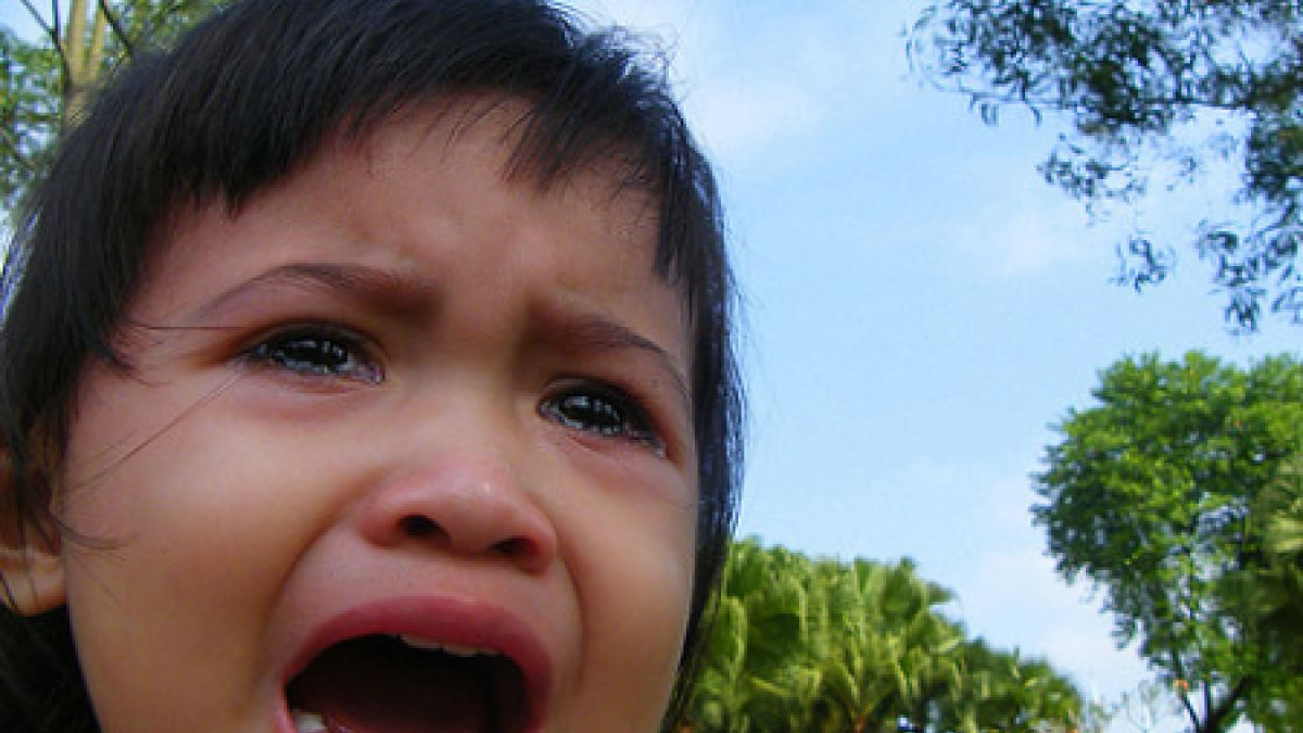 kid crying while holding cross